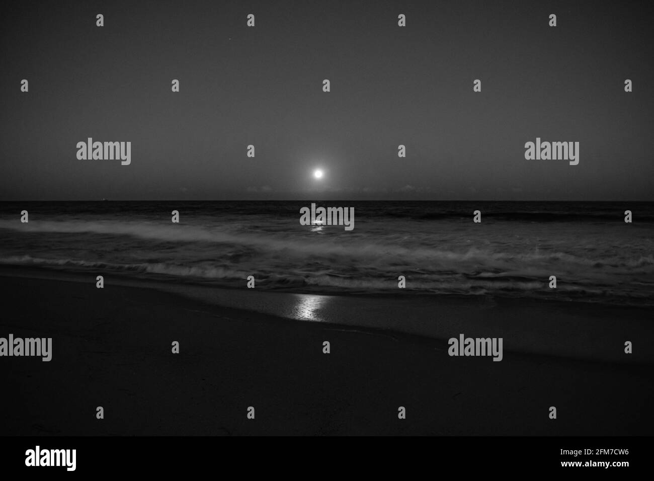 Grayscale shot of the beach under a clear sky at sunset Stock Photo - Alamy