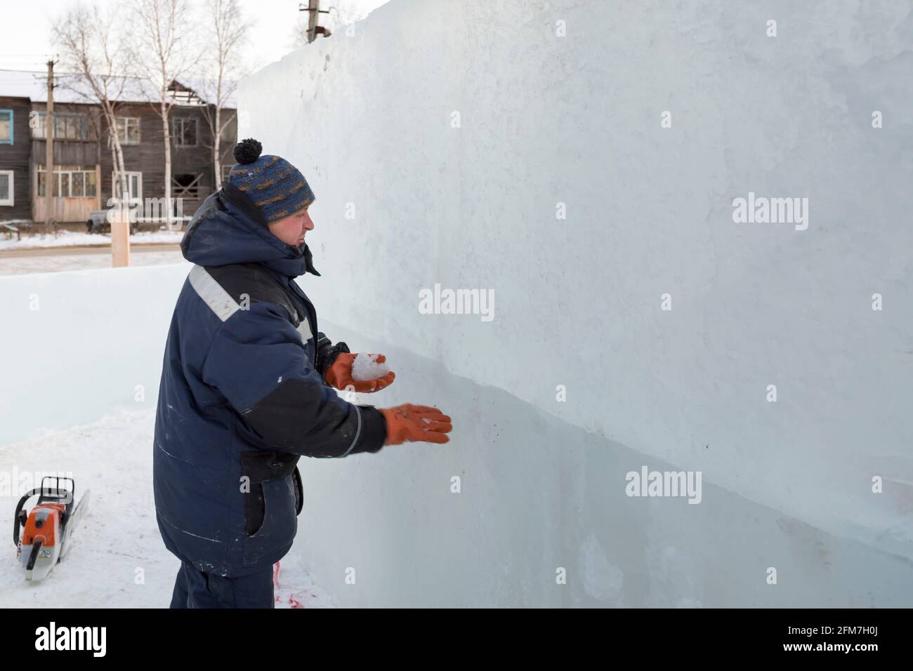 The installer at the construction site of the ice town covers the ...