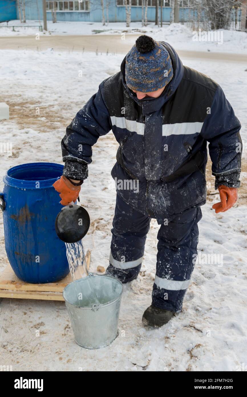 The installer at the construction site of the ice town pours water from ...