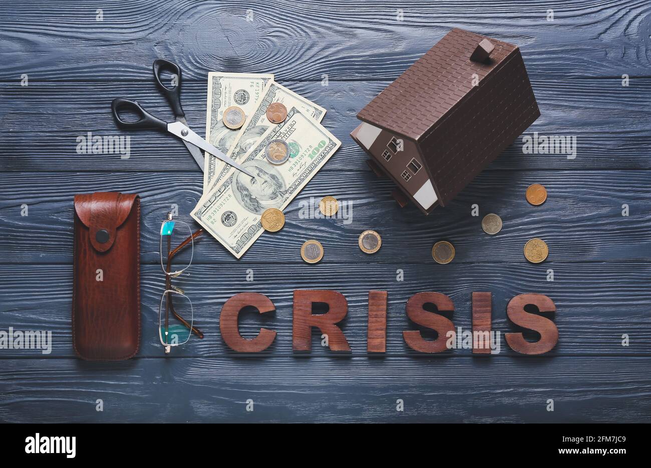 Money with scissors, model of house and word CRISIS on wooden ...