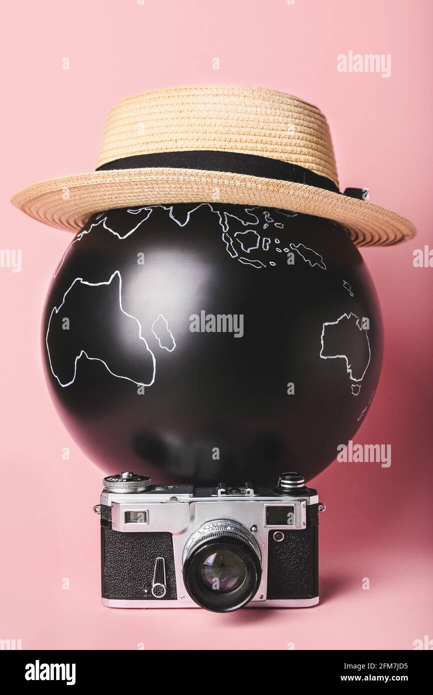 Globe with photo camera and hat on color background Stock Photo - Alamy