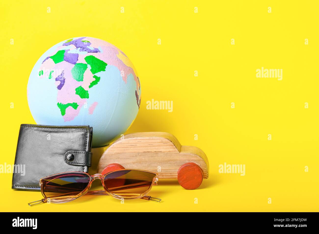 Globe with wooden car, wallet and sunglasses on color background Stock ...