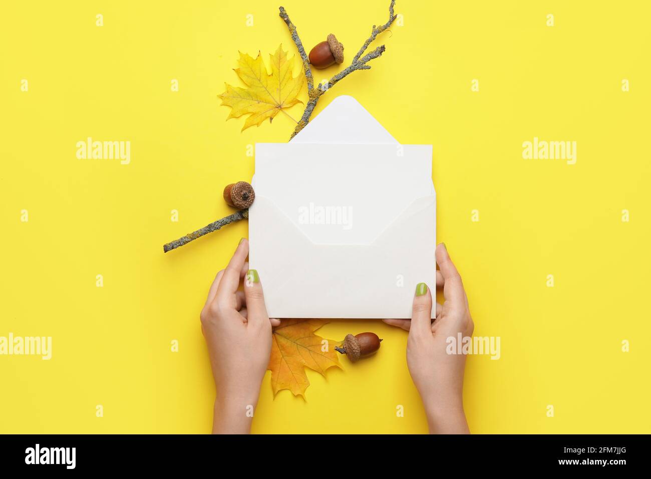 Female hands with envelope, blank card, acorns and autumn leaves on ...