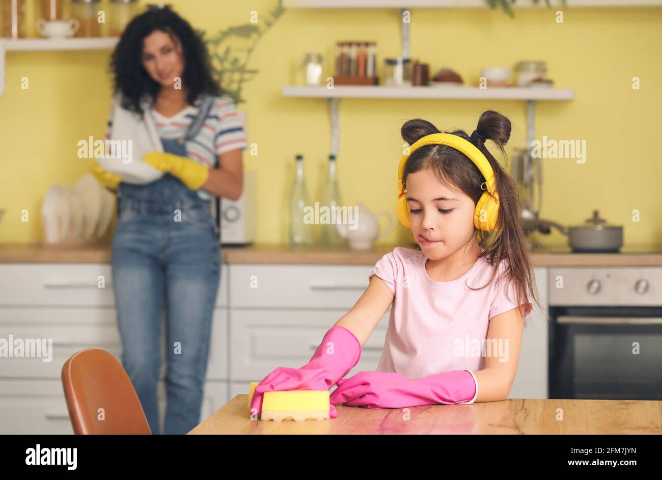 Cute little girl cleaning table in kitchen Stock Photo - Alamy