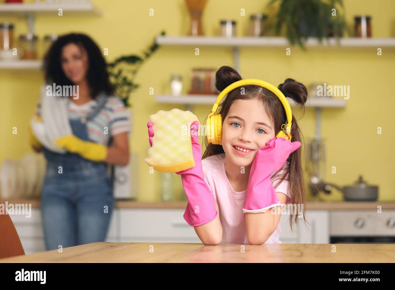 Cute little girl cleaning table in kitchen Stock Photo - Alamy