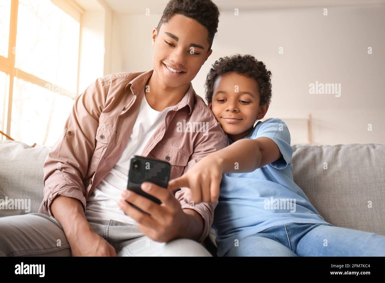 African-American boys using mobile phone in room Stock Photo - Alamy