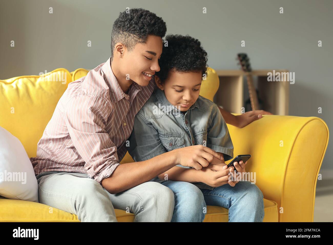 African-American boys using mobile phone in room Stock Photo - Alamy