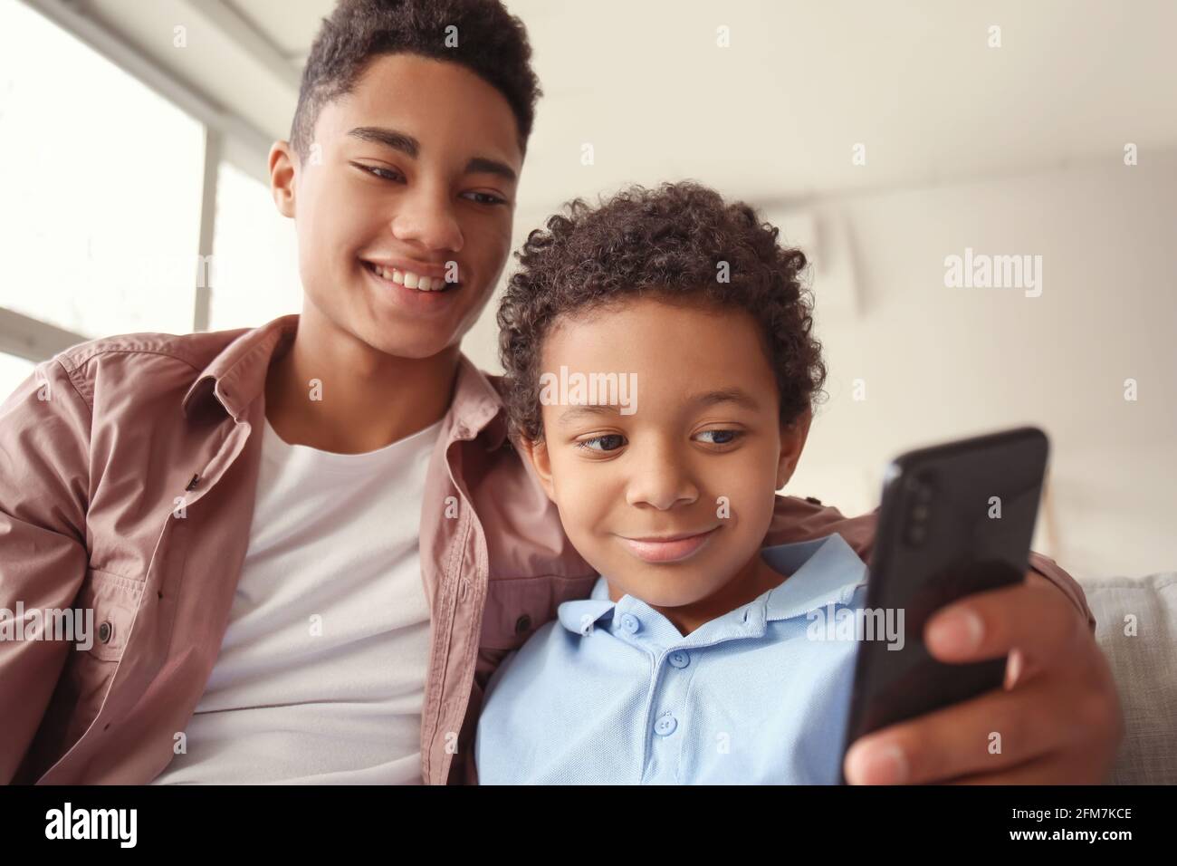 African-American boys using mobile phone in room Stock Photo - Alamy