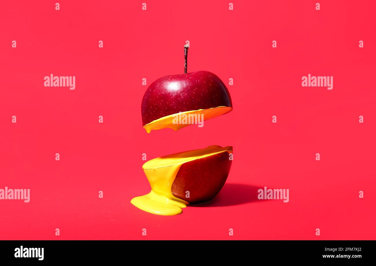 Cut red apple with liquid on color background Stock Photo - Alamy