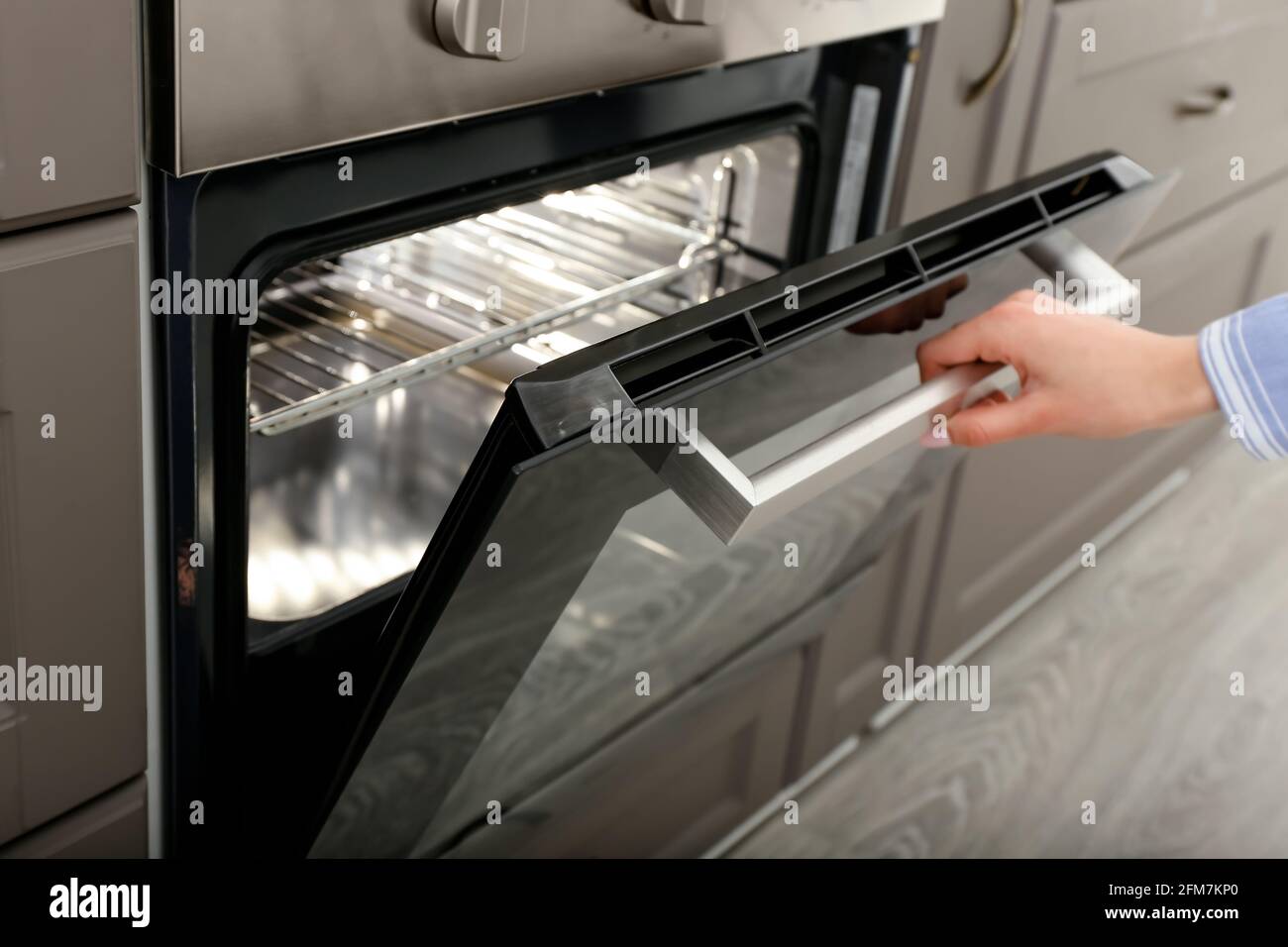 Woman opening oven in kitchen Stock Photo - Alamy