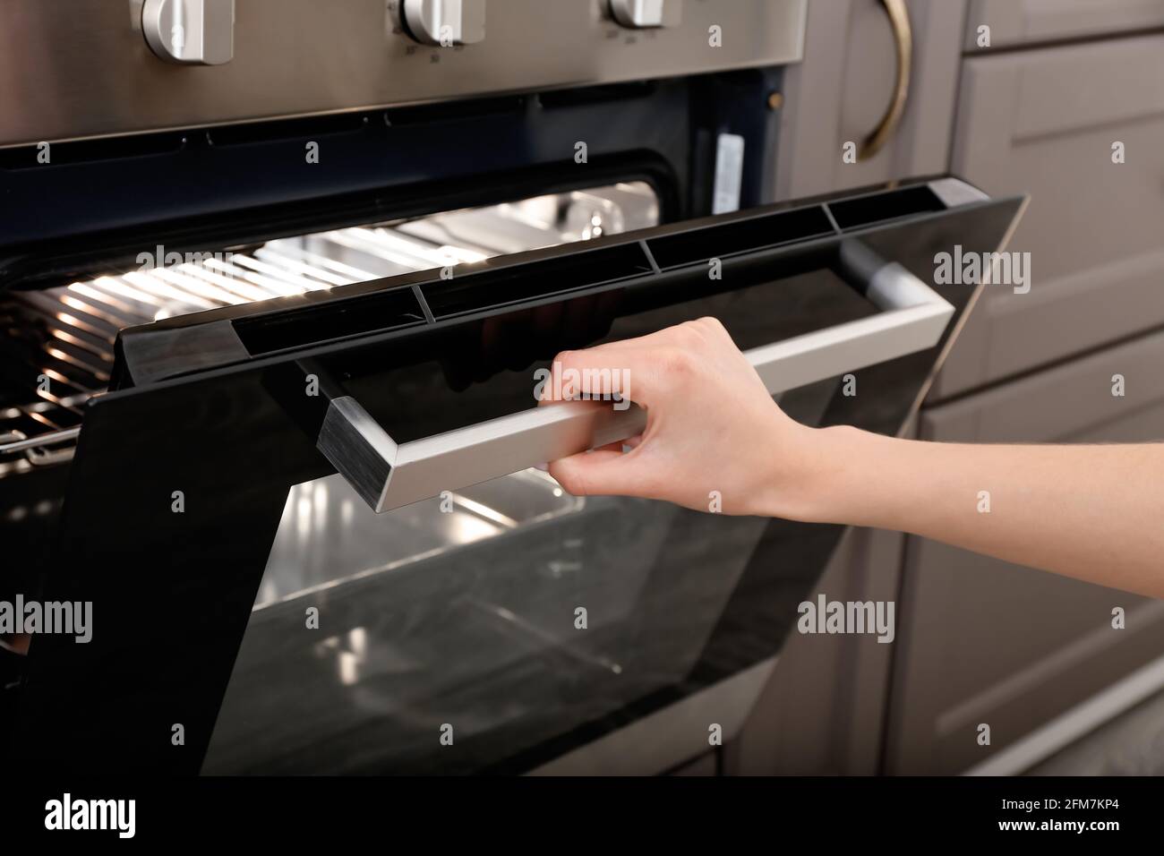 Woman opening oven in kitchen Stock Photo - Alamy