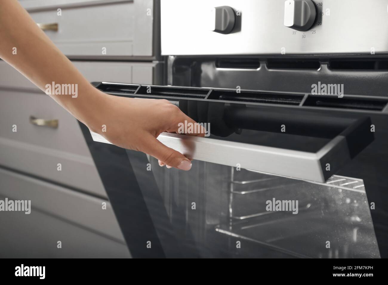 Woman opening oven in kitchen Stock Photo - Alamy