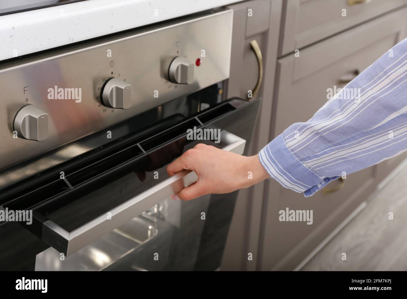 Woman opening oven in kitchen Stock Photo - Alamy