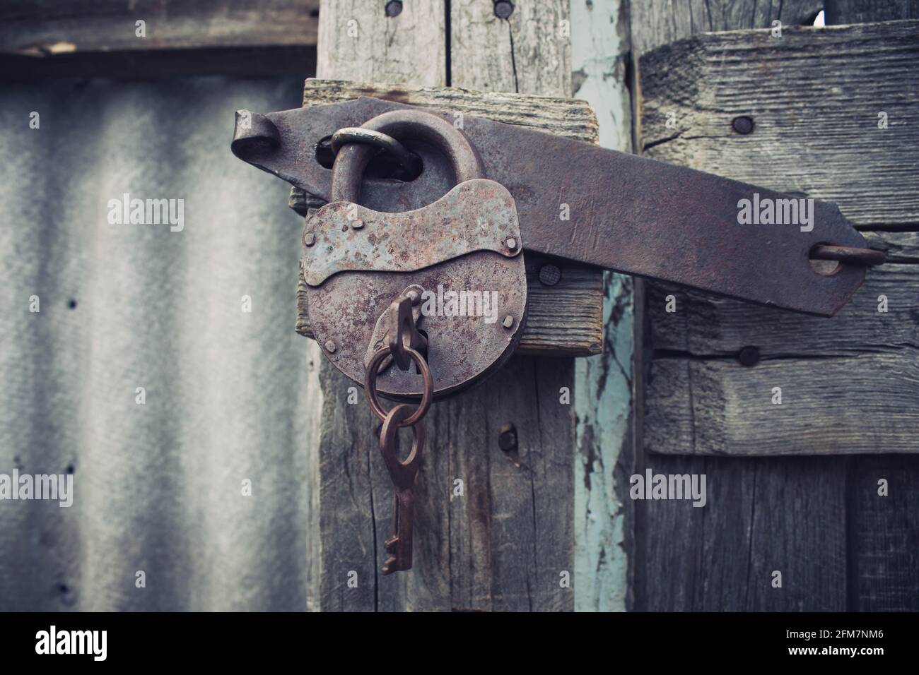 Iron rusty lock with a key. Closed door. Locked gates to the barn lock ...