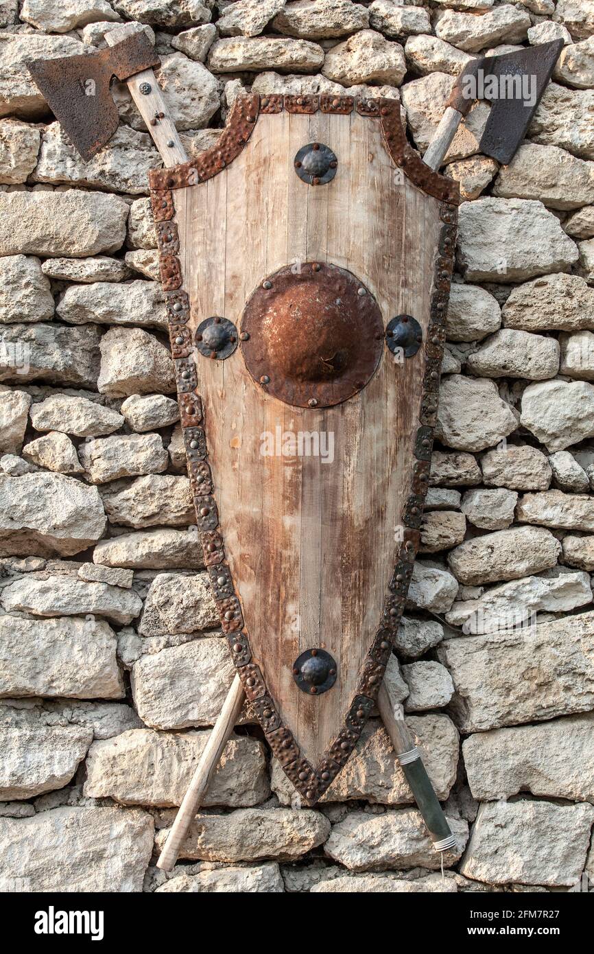 Ancient weapons wall. Wooden shield with iron accents and axes Stock ...