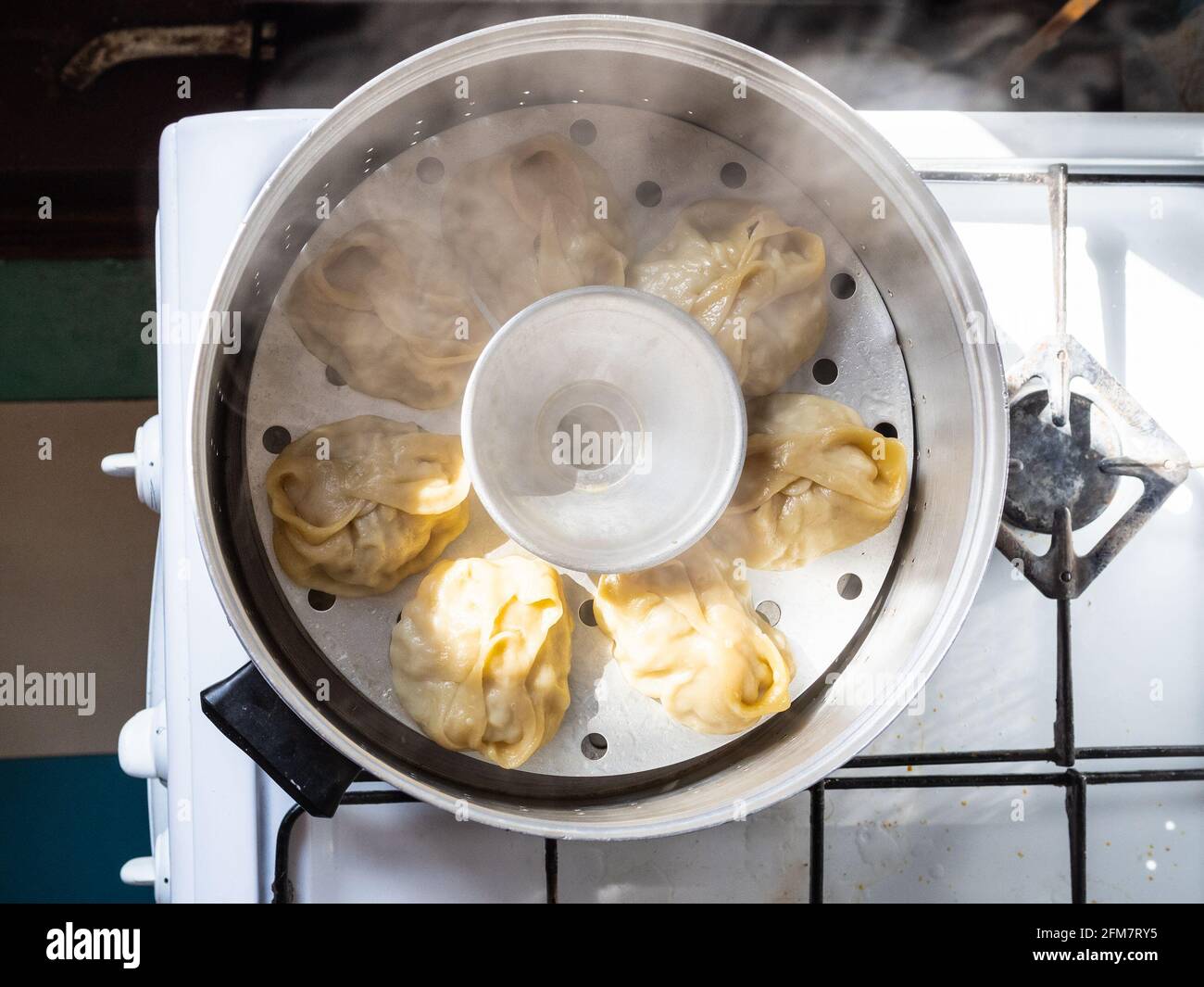 top view of homemade manti are cooking in aluminum steamer on stove in ...
