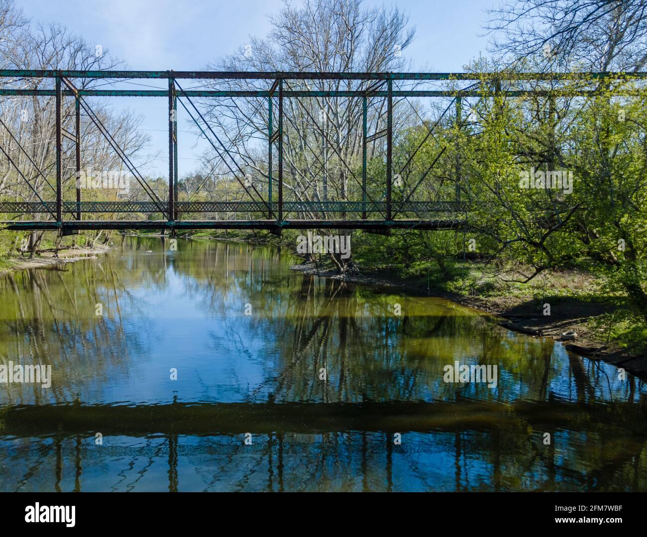 A rusty abandoned steel truss bridge over a small the slow moving ...