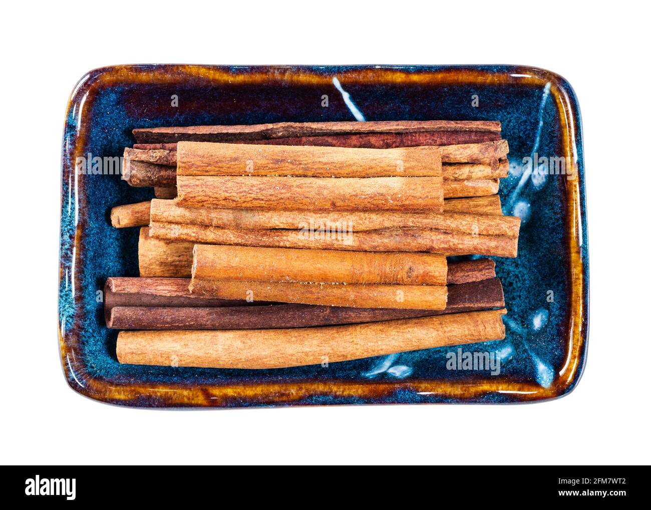 top view of sticks of cassia cinnamon in ceramic bowl cutout on white ...