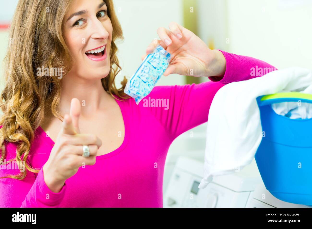 Young woman with laundry basket and detergent in a laundrette she ...