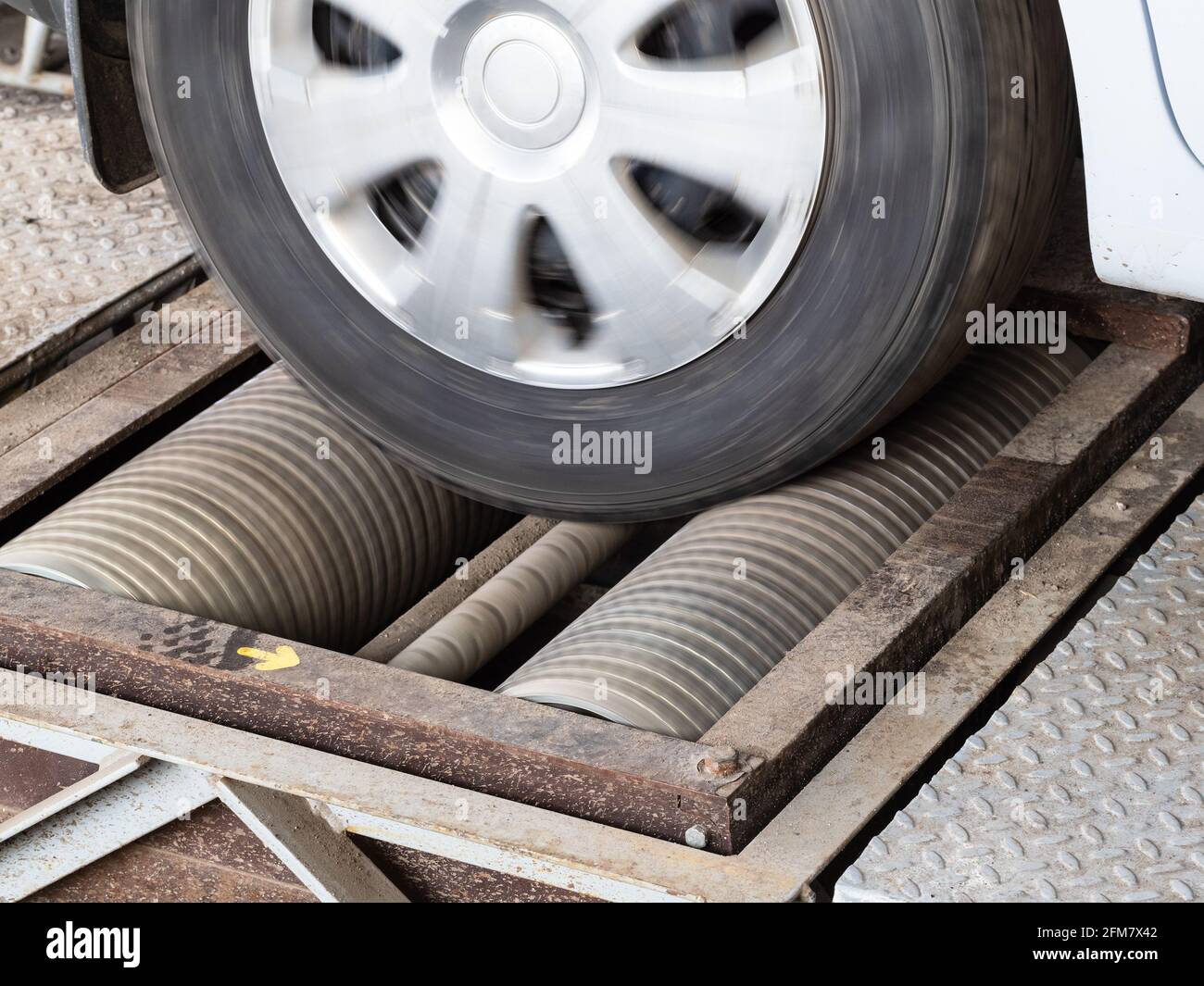 rotating rear wheel on roller brake tester on MOT inspection lane in ...
