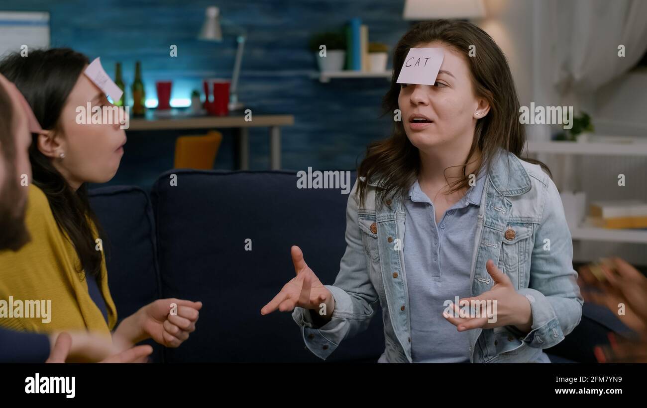 Multiethnic friends sitting on couch late at night playing fuuny guess ...