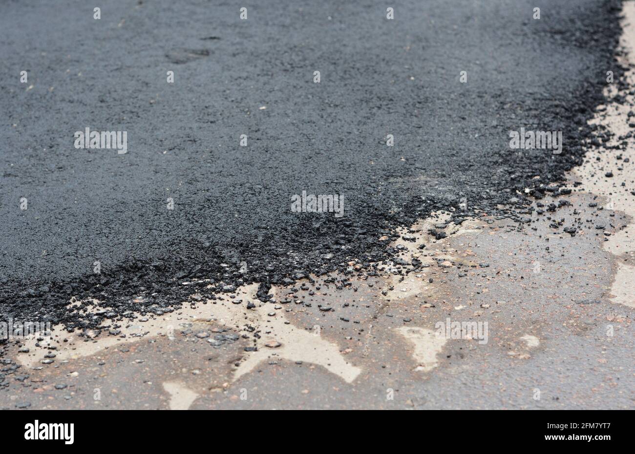 A close-up of a pothole repair on the road, repaired patched asphalt ...