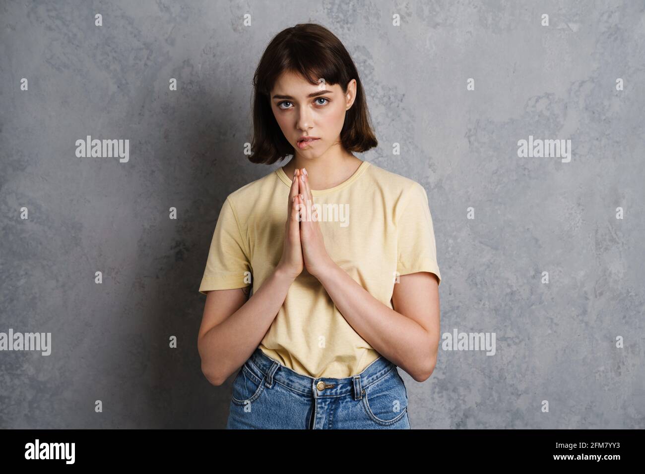 Portrait of a beautiful pleading young girl in casual clothes asking ...
