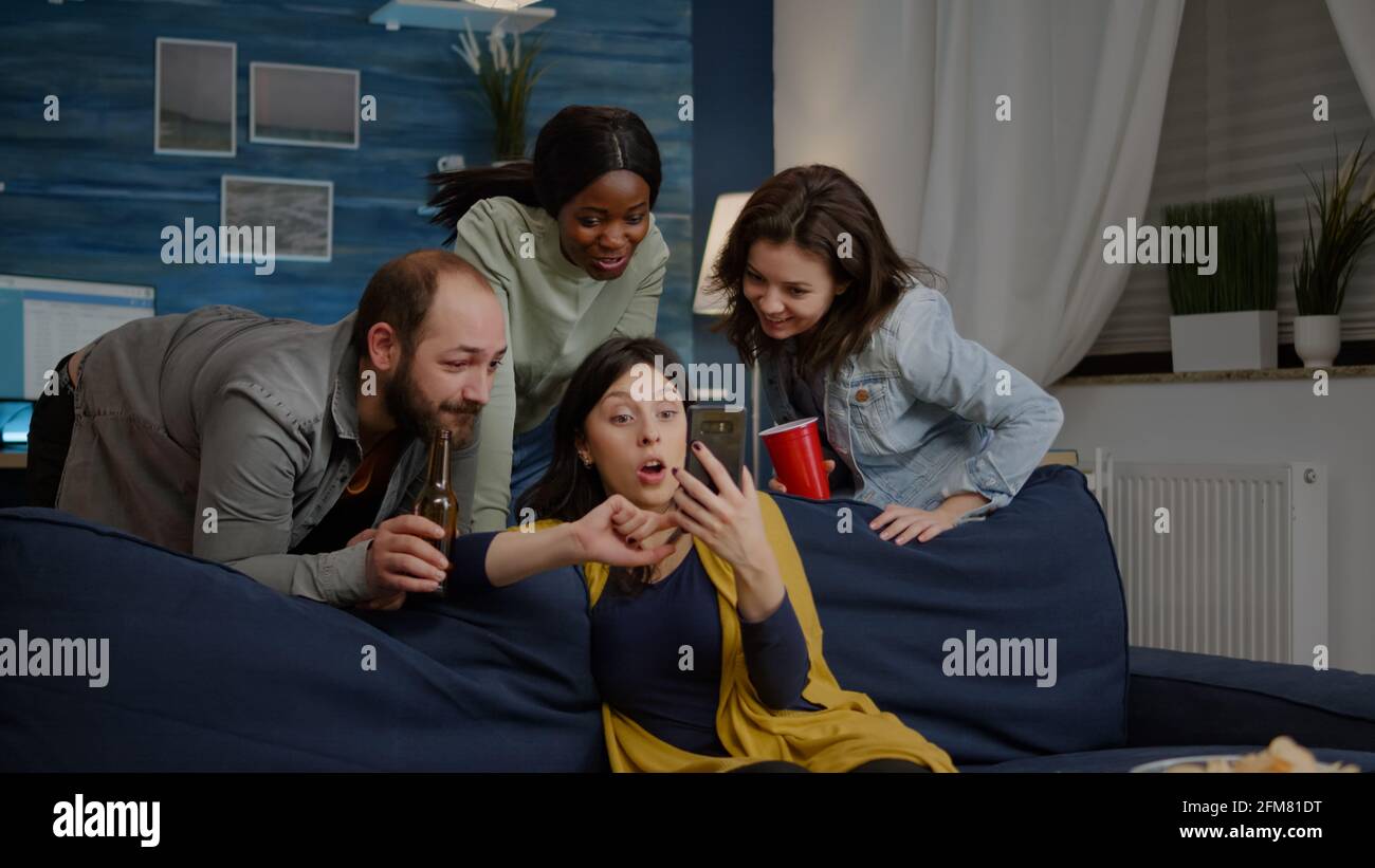 Multiracial friends hanging out late at night watching funny ...