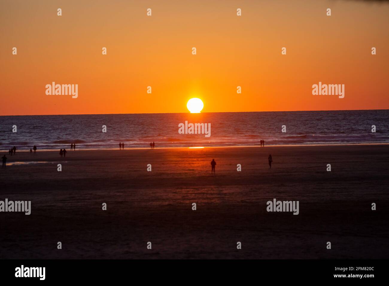 People stand on the beach to watch the Sunset over Perranporth Beach in ...