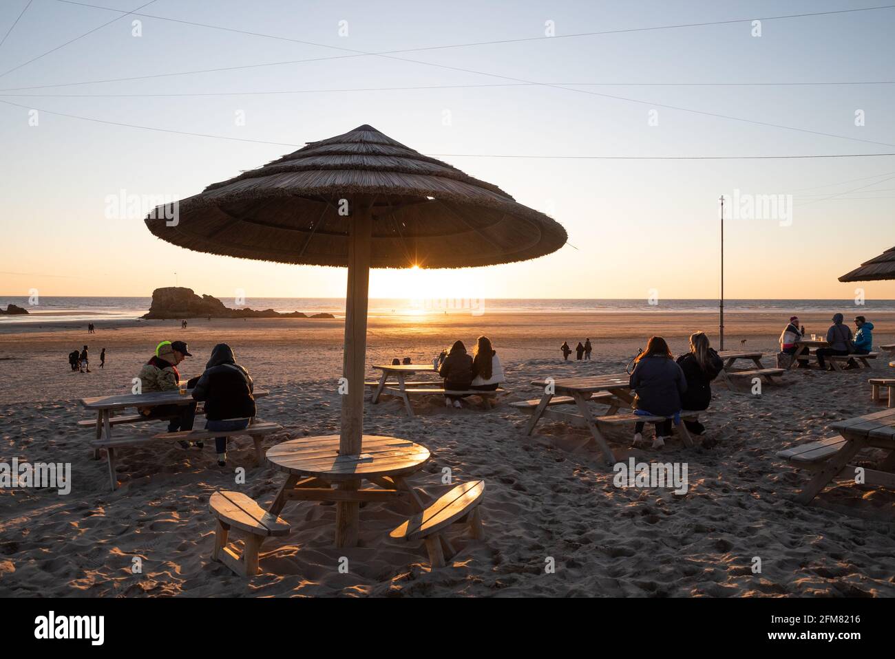 People stand on the beach to watch the Sunset over Perranporth Beach in ...