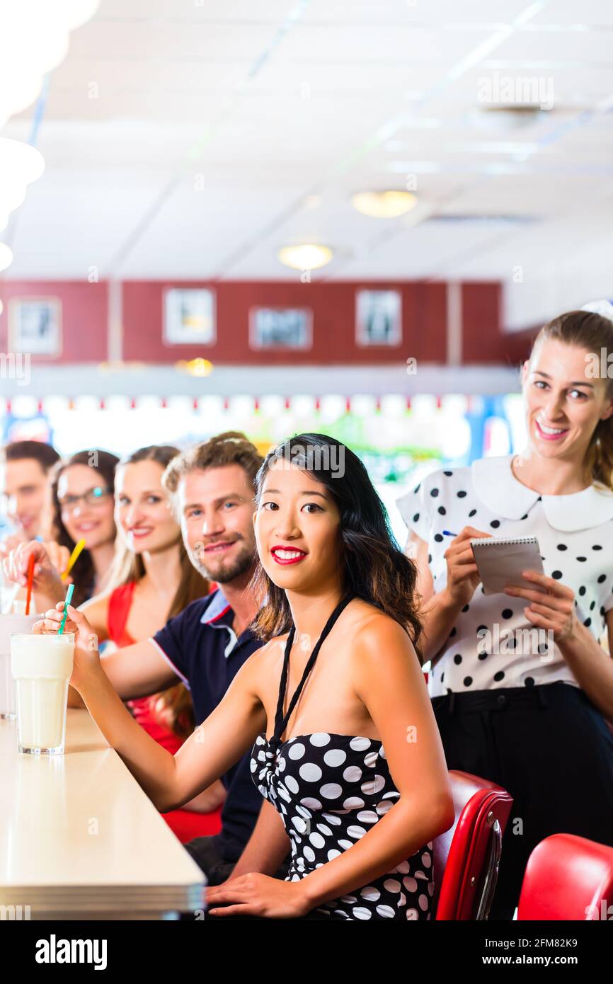 Friends or couples eating fast food and drinking milk shakes on bar in ...