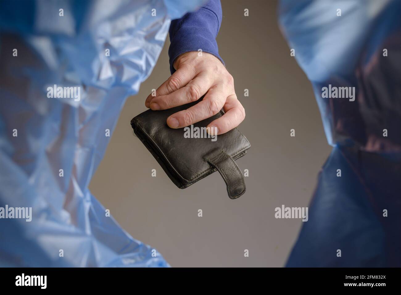 A hand tosses an old black wallet into a trash can. Man holds empty ...