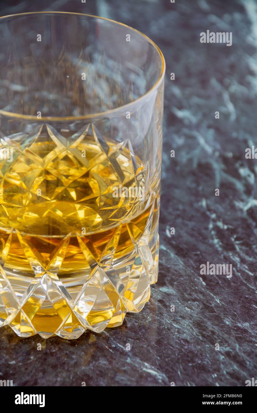 Top view of glass with whiskey on blue marble, vertical, with copy ...