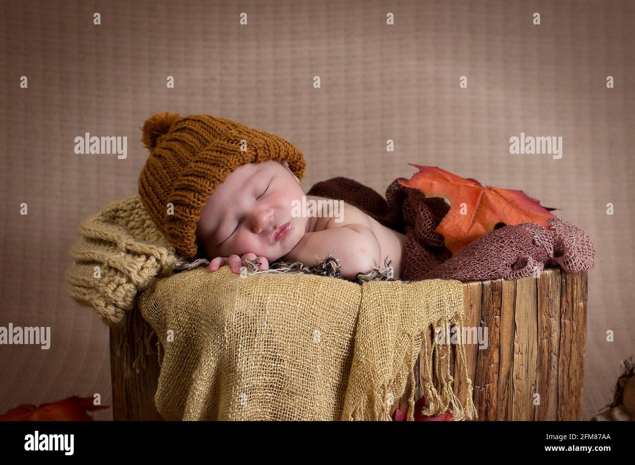 Adorable newborn Caucasian baby boy with a bonnet sleeping on a basket ...