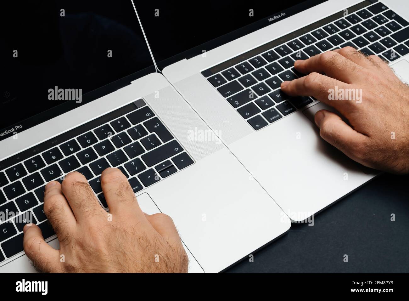 Male hand operating two laptop simultaneously professional Apple ...