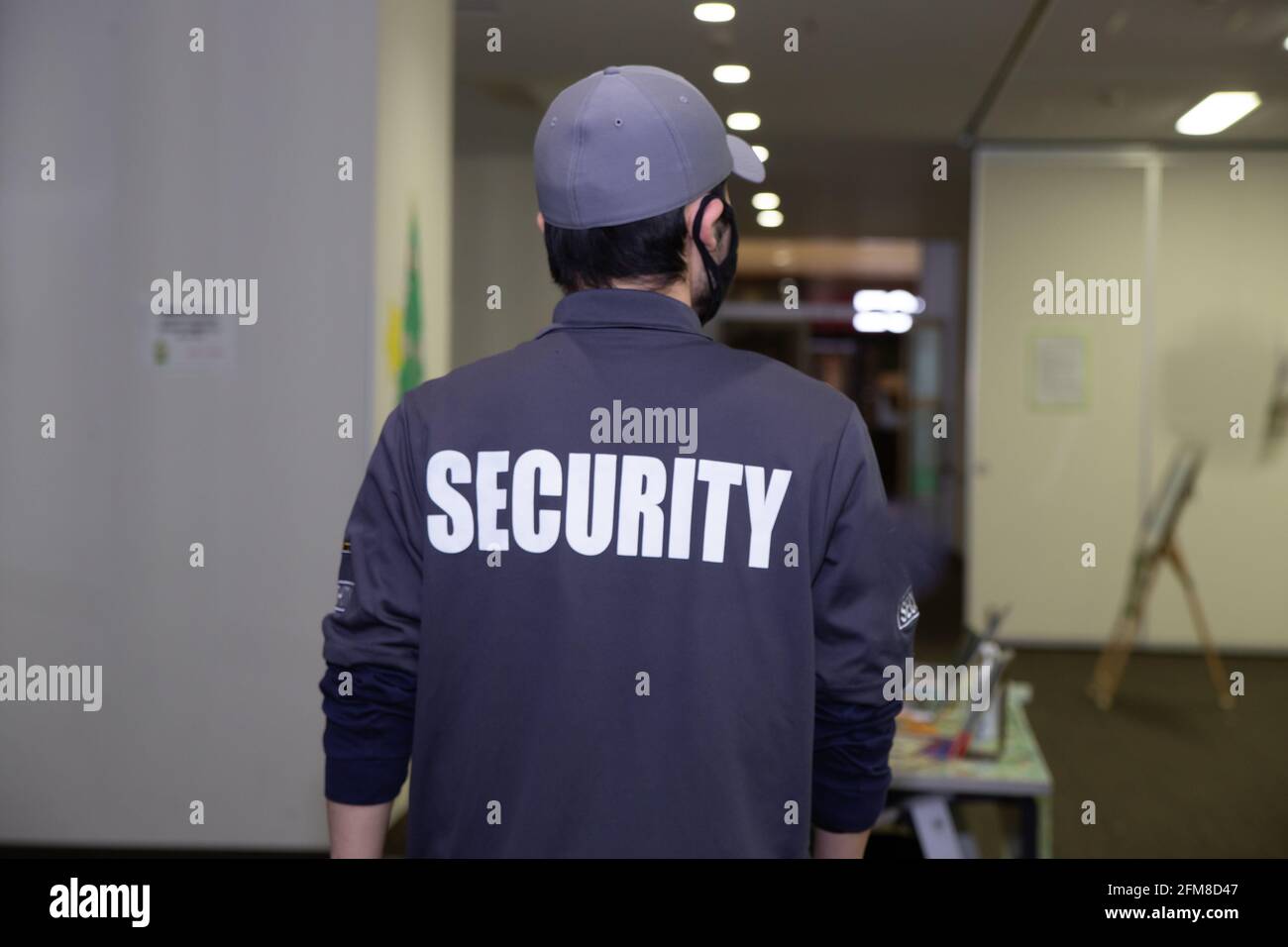 A rear view of security guard in uniform patrolling in commercial ...