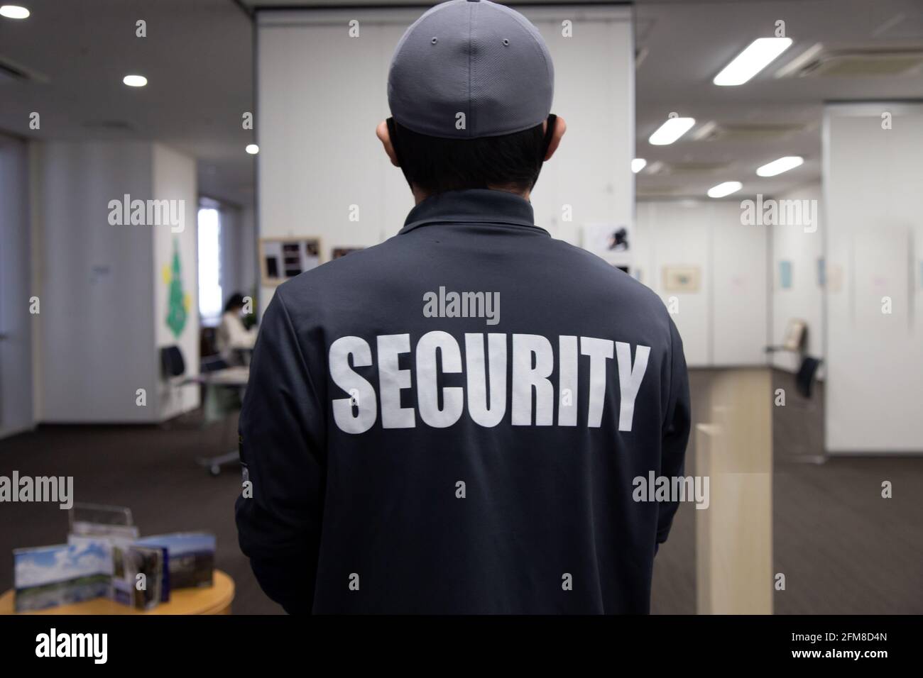 A rear view of security guard in uniform patrolling in commercial ...