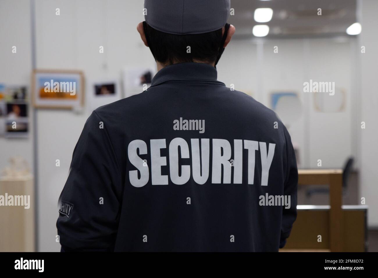A rear view of security guard in uniform patrolling in commercial ...