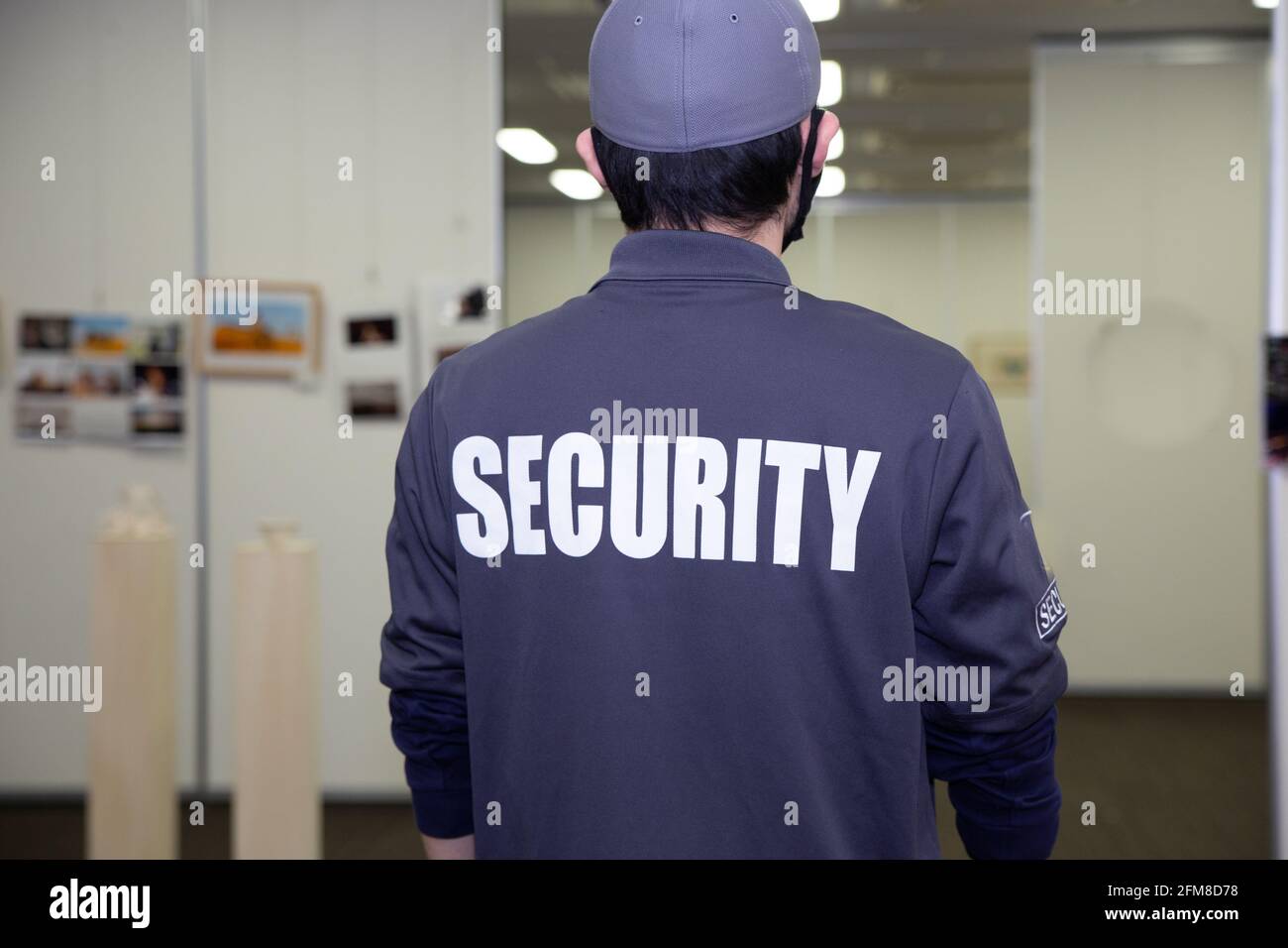 A rear view of security guard in uniform patrolling in commercial ...