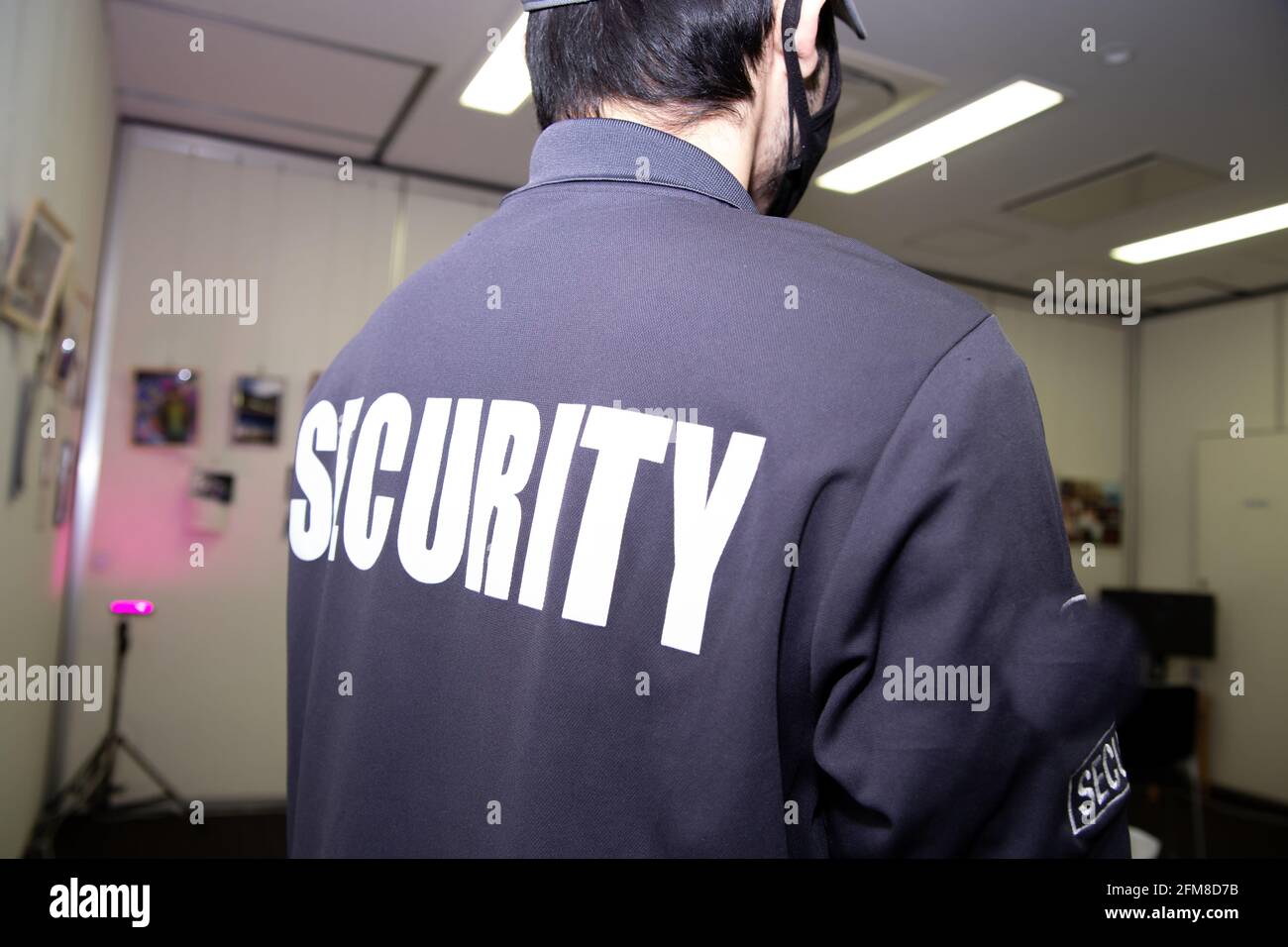 A rear view of security guard in uniform patrolling in commercial ...