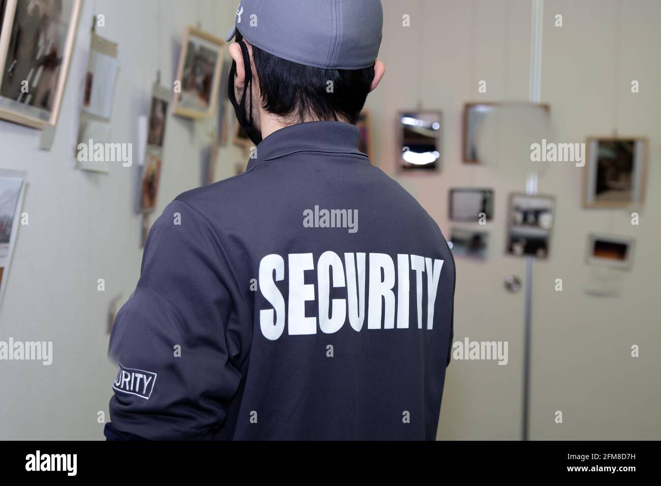 A rear view of security guard in uniform patrolling in commercial ...
