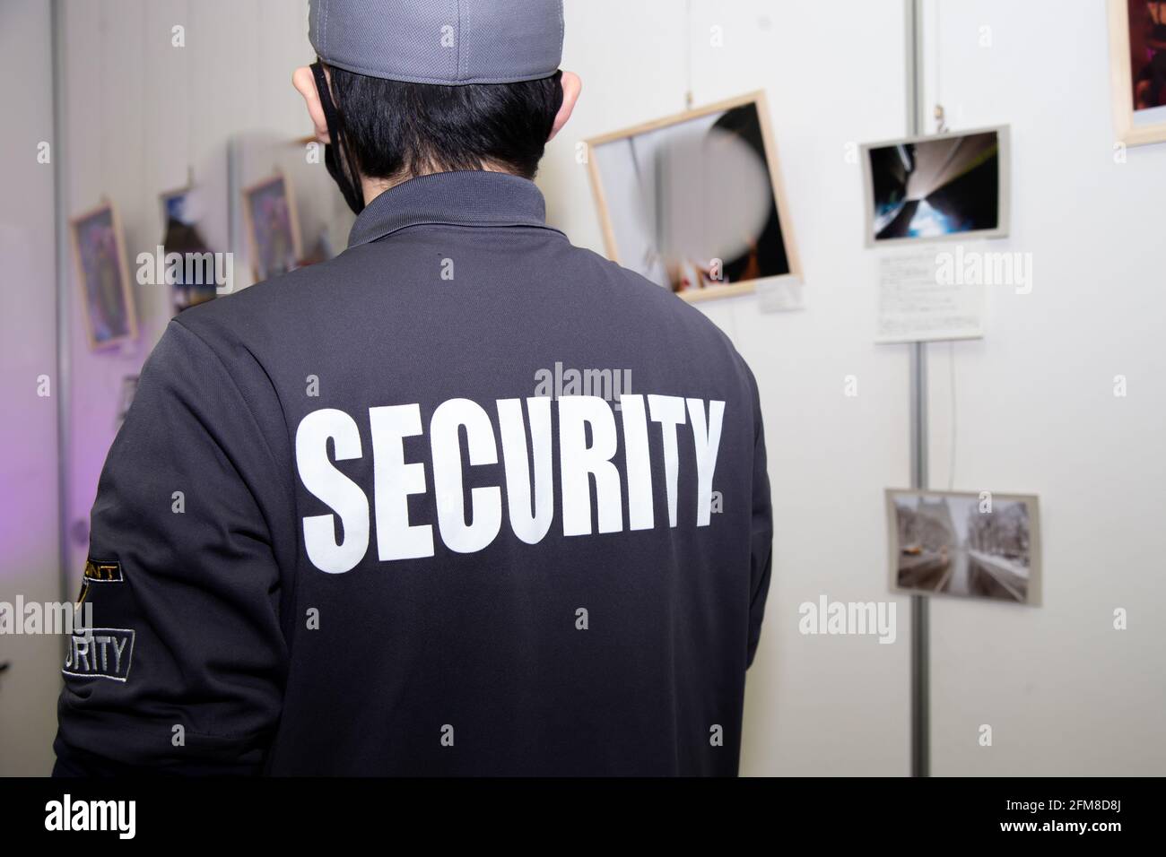 A rear view of security guard in uniform patrolling in commercial ...