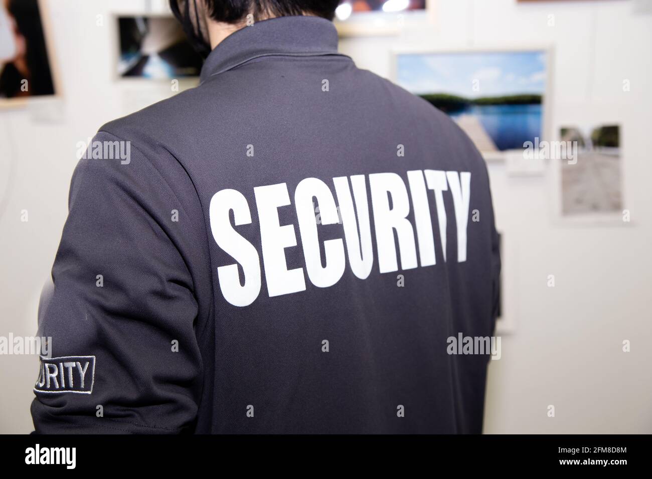 A rear view of security guard in uniform patrolling in commercial ...