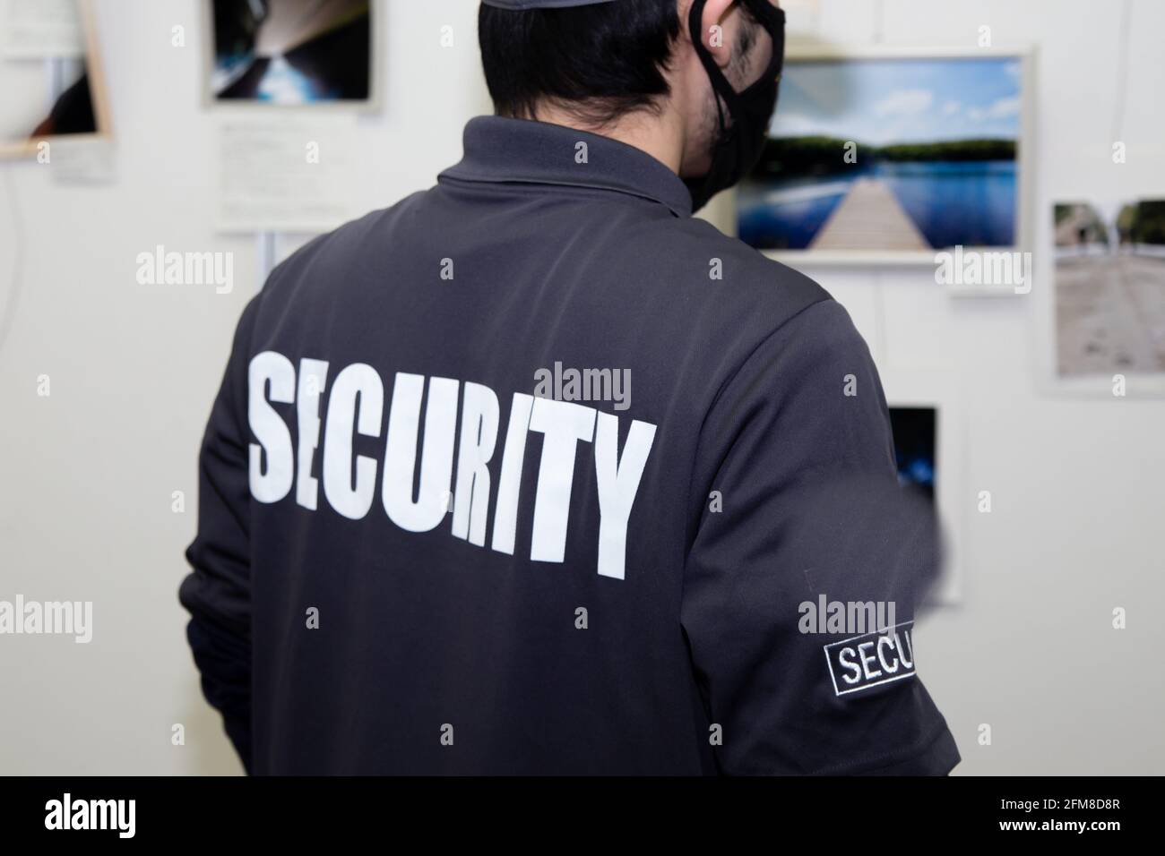 A rear view of security guard in uniform patrolling in commercial ...