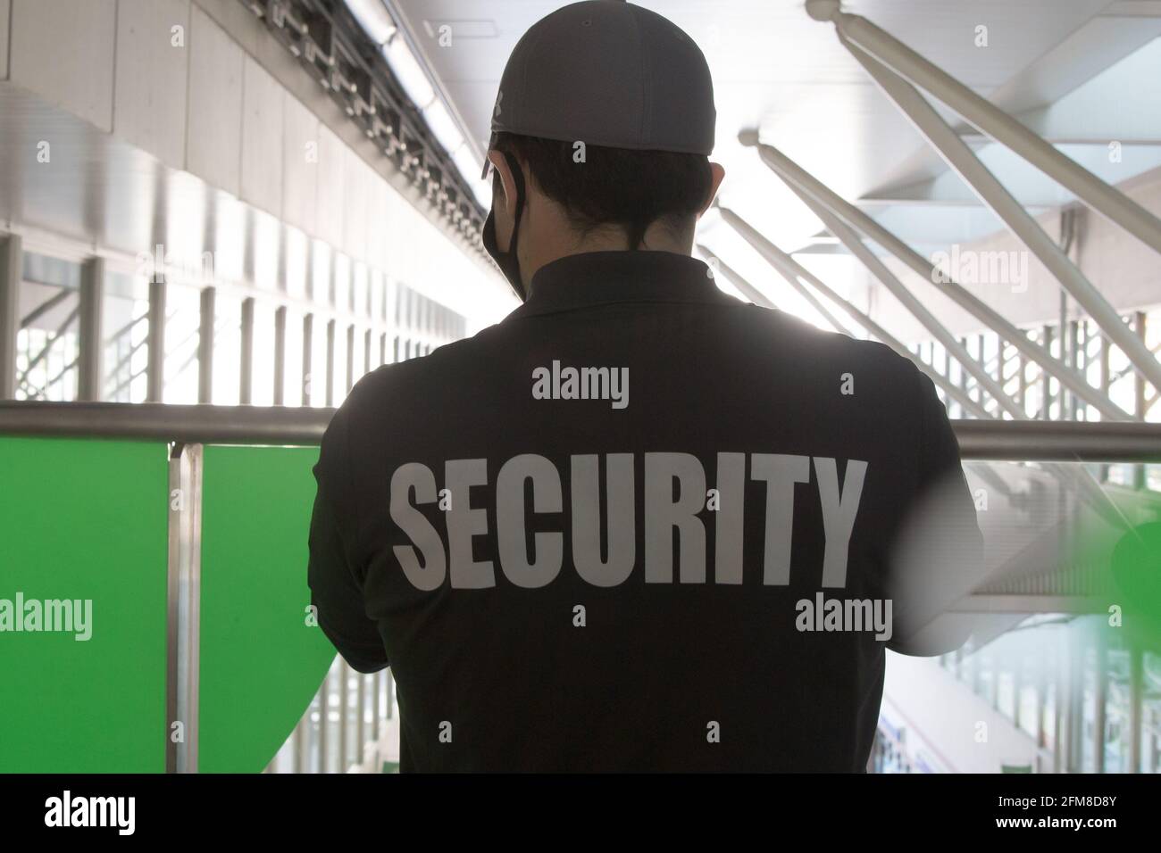 A rear view of security guard in uniform patrolling in commercial ...