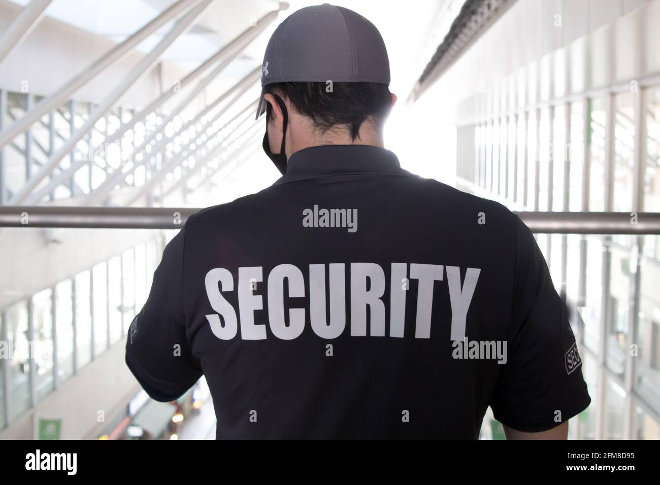 A rear view of security guard in uniform patrolling in commercial ...