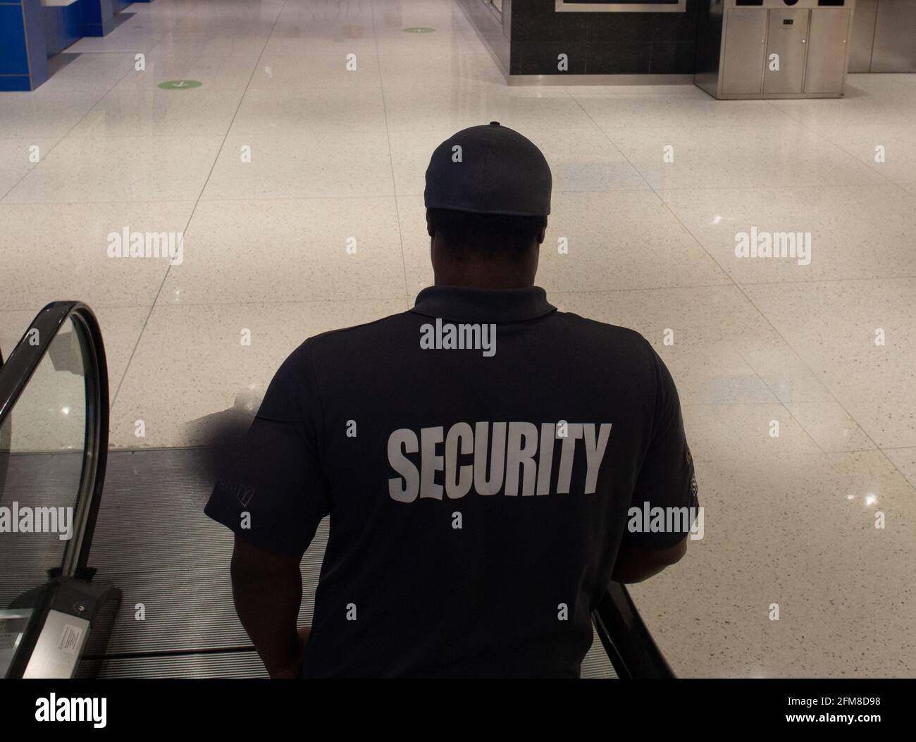 A rear view of security guard in uniform patrolling in commercial ...