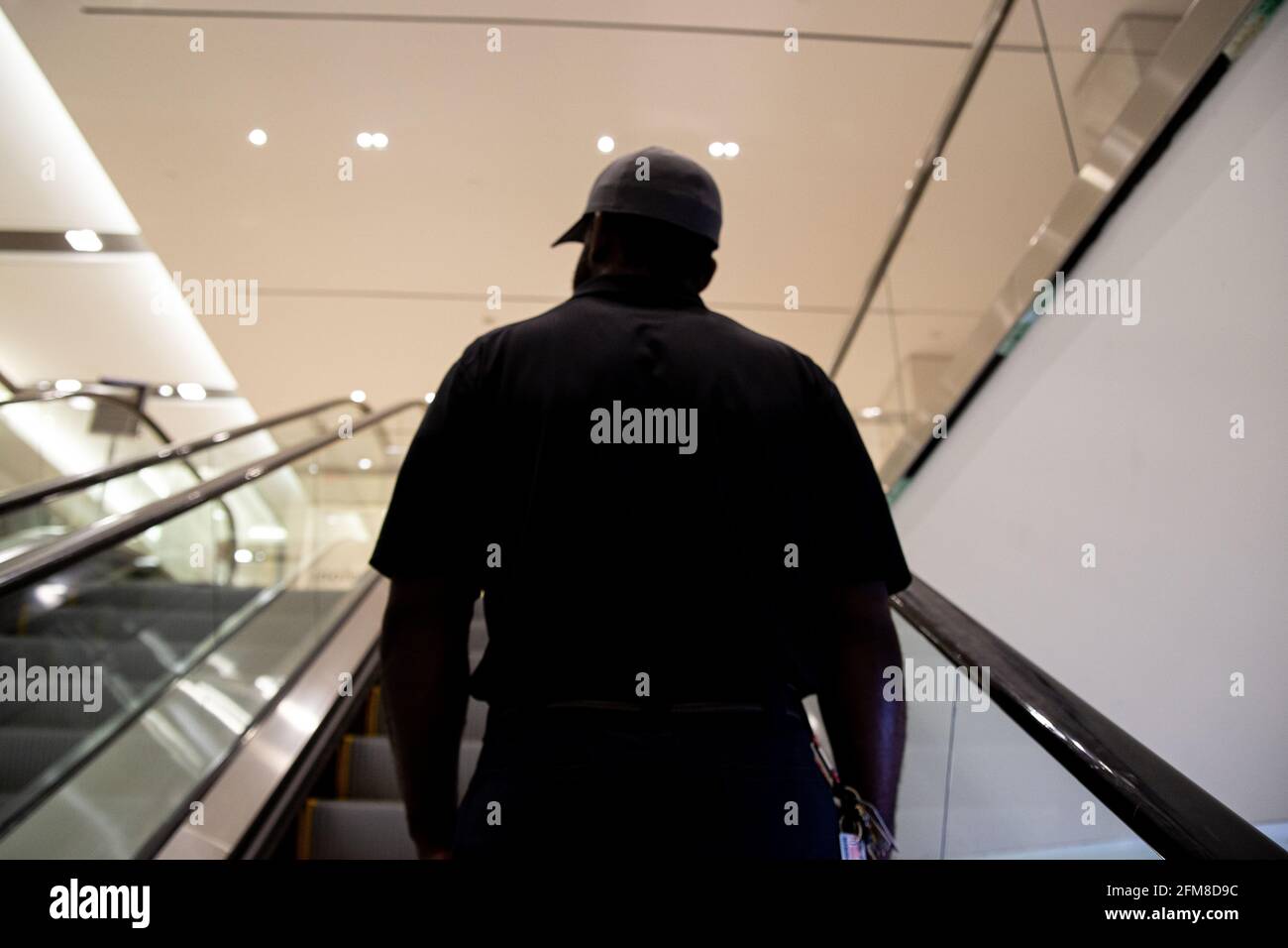 A rear view of security guard in uniform patrolling in commercial ...