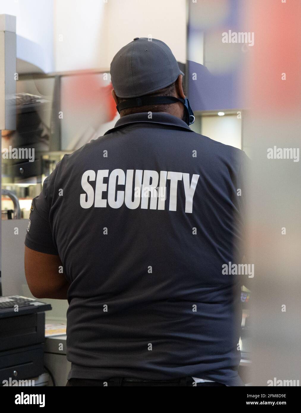 A rear view of security guard in uniform patrolling in commercial ...