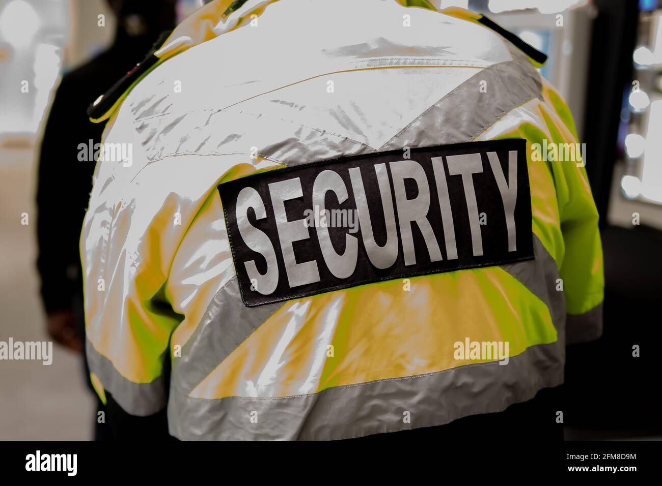 A rear view of security guard in uniform patrolling in commercial ...